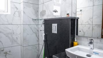 Casa de banho com sanita branca, lavatório com espelho e zona de duche.