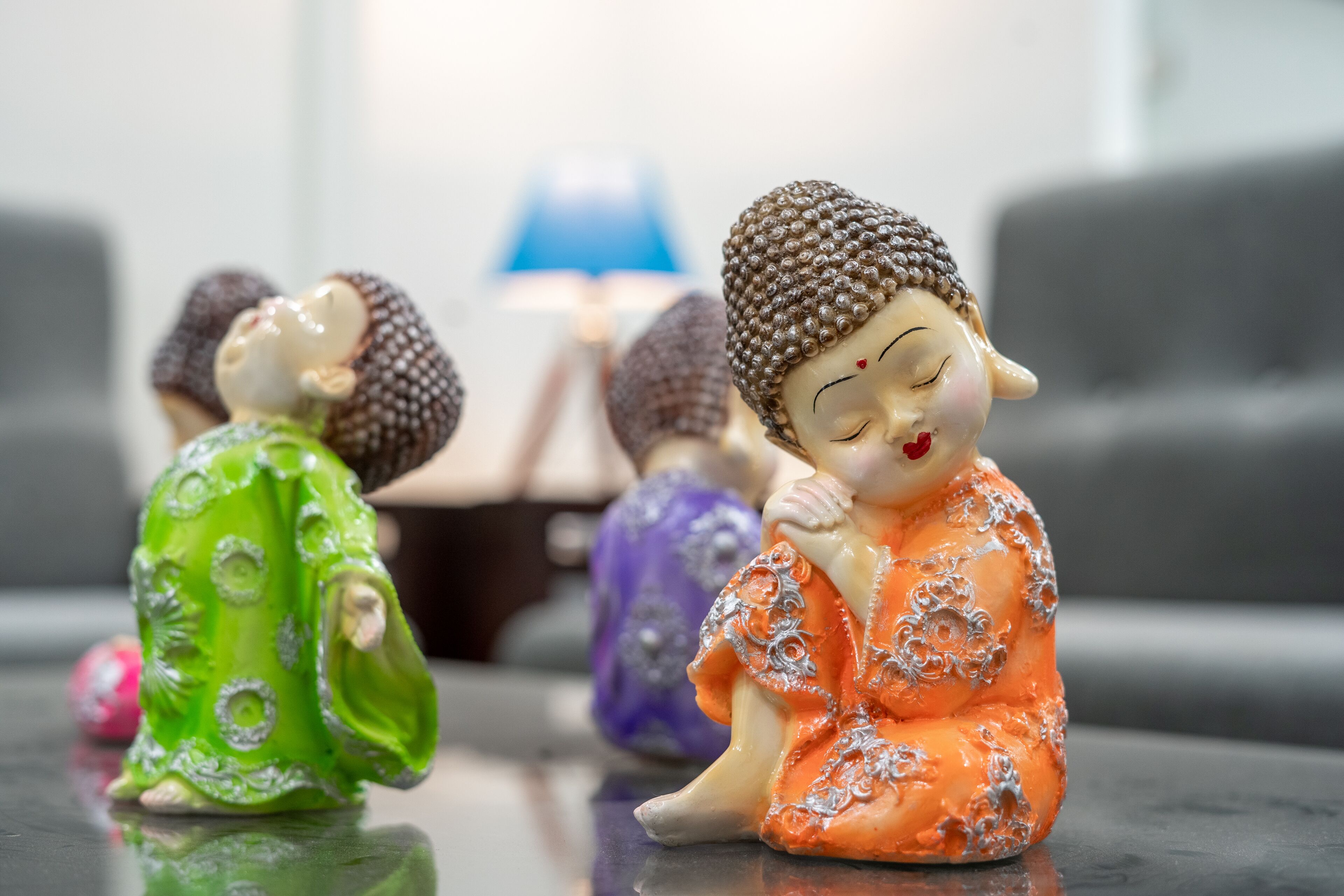 Uma estátua de Buda em vestes laranja e verde sobre uma mesa.