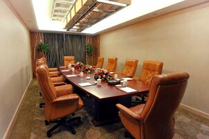 Uma sala de conferências com uma mesa comprida, cadeiras de couro e um lustre.