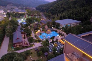 Um resort com piscina, quartos para hóspedes e montanhas ao fundo.