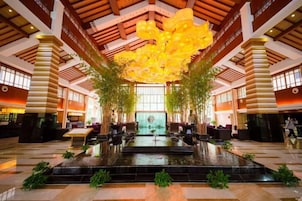 Um hall amplo com um recurso central de água, áreas de estar e um design de teto marcante.