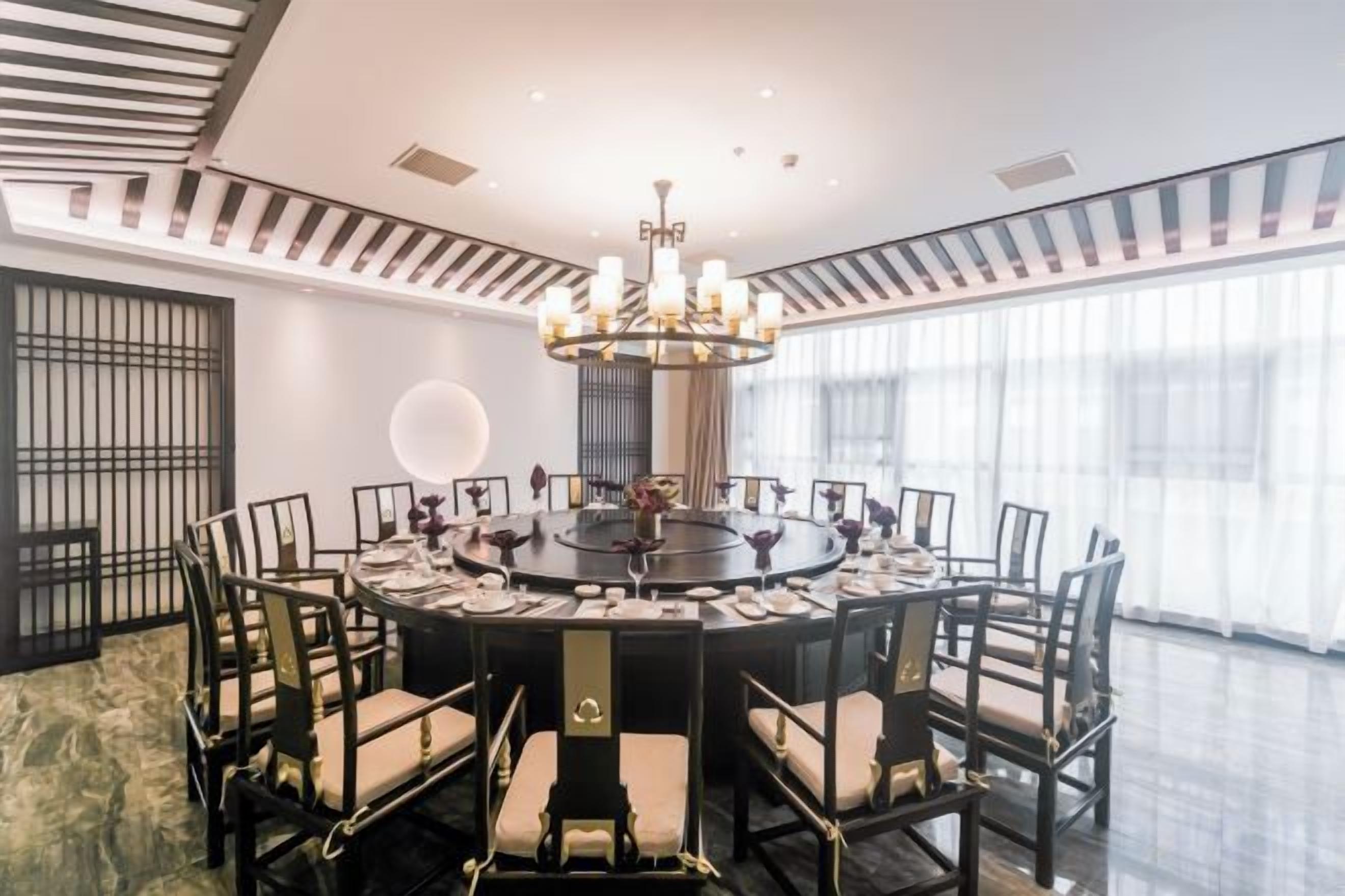 Uma sala de conferências com mesa redonda, cadeiras e um lustre.