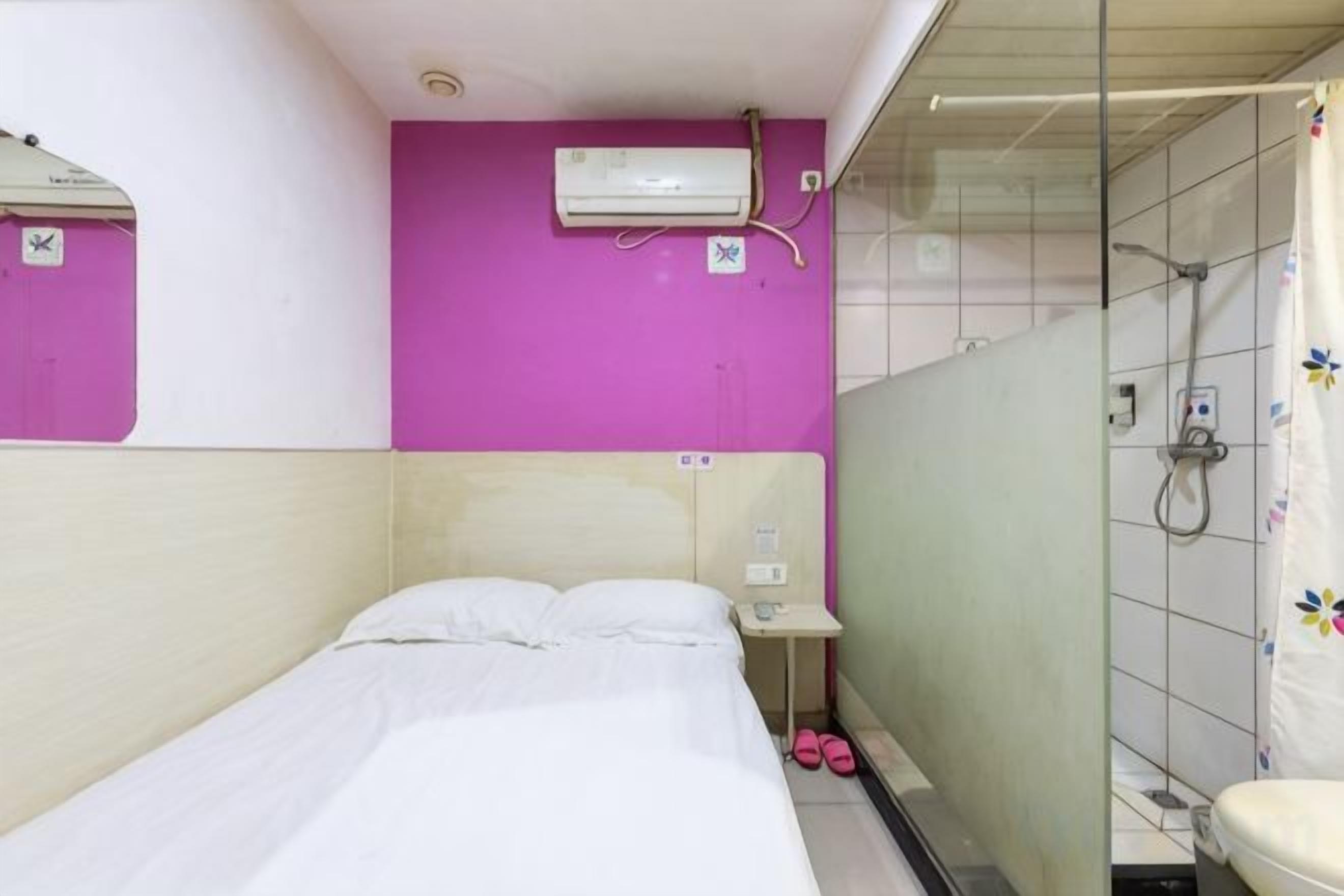 Quarto com cama, mesinha de cabeceira, ar condicionado e chuveiro.