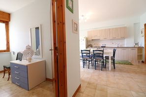 Quarto com guarda-roupa de madeira, secretária com gavetas, uma cadeira e mesa de jantar com cadeiras.