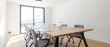 Sala de conferência com uma mesa comprida, cadeiras e vista através de uma grande janela.