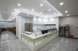 Cozinha moderna com ilha central, eletrodomésticos embutidos e área de jantar com cadeiras.