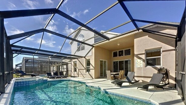 Piscina com espreguiçadeiras e área de varanda coberta.