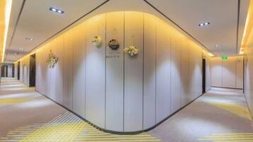 Corredor de hotel com parede curva, balcão de recepção e piso coberto por carpete.