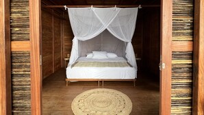 Um quarto de madeira com uma cama sob um dossel, um tapete tecido no chão e painéis de madeira nas paredes.