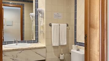 Casa de banho com lavatório de mármore, secador de cabelo, sanita e chão em azulejos azuis.