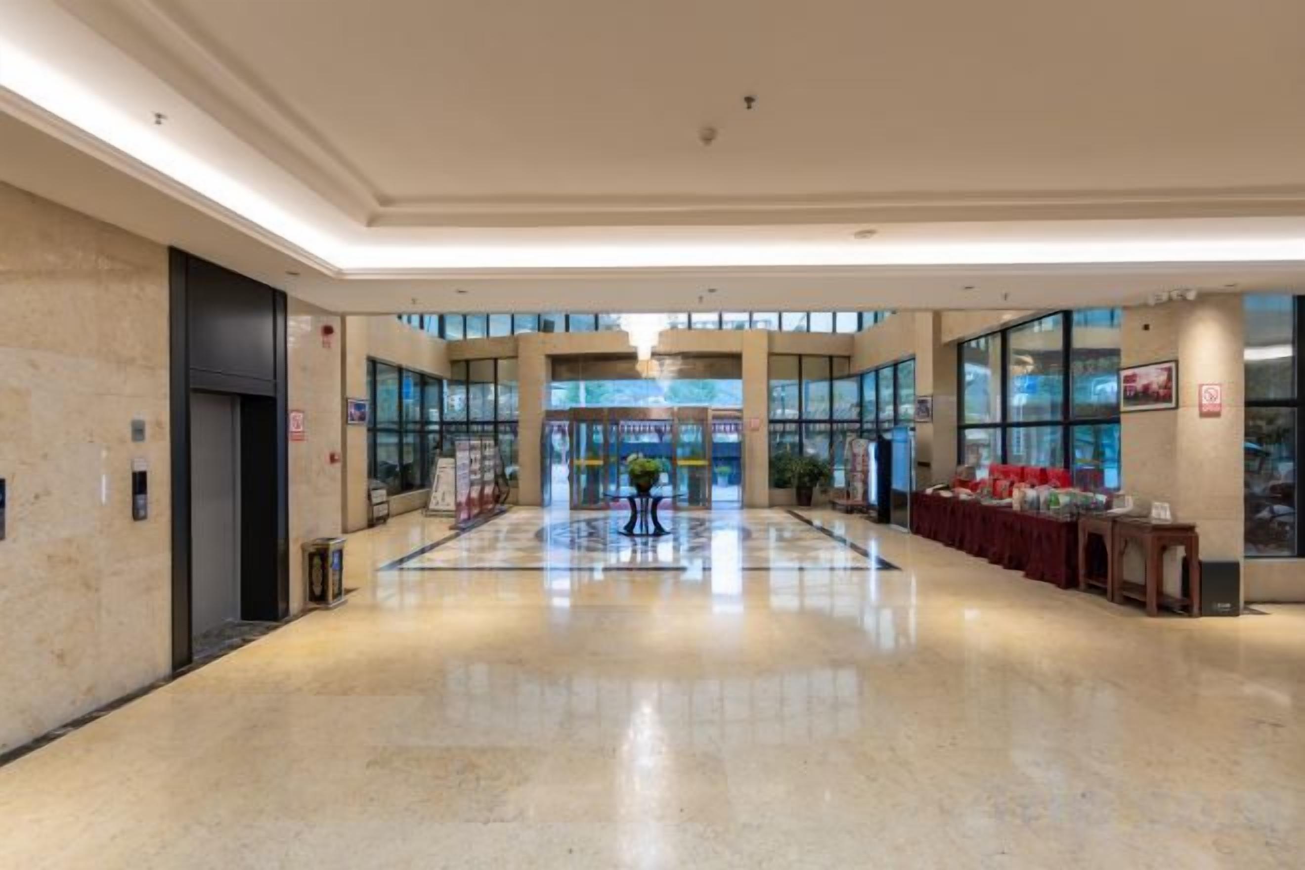 Um hall amplo com piso lustroso, grandes janelas e um balcão de recepção.