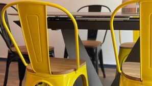 Uma sala de jantar com cadeiras amarelas e uma mesa.