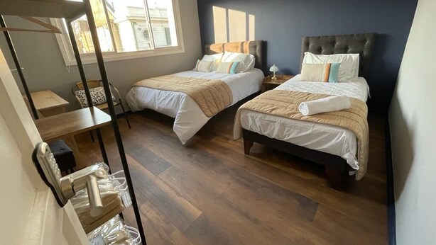 Quarto com duas camas, uma janela e piso de madeira.