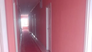Um corredor extenso com carpete vermelho e paredes brancas.