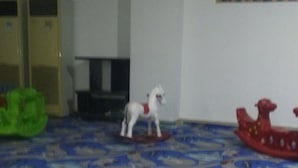 Um quarto com um piso estampado, um balanço de madeira branco, um balanço de madeira vermelho e uma cadeira verde.