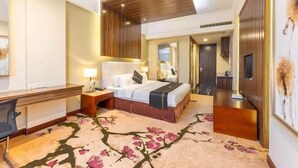 Quarto de hotel com cama, escrivaninha e um espelho grande.
