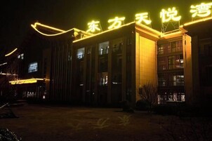 Um edifício com letreiros iluminados em idioma estrangeiro, sugerindo um hotel ou estabelecimento similar.