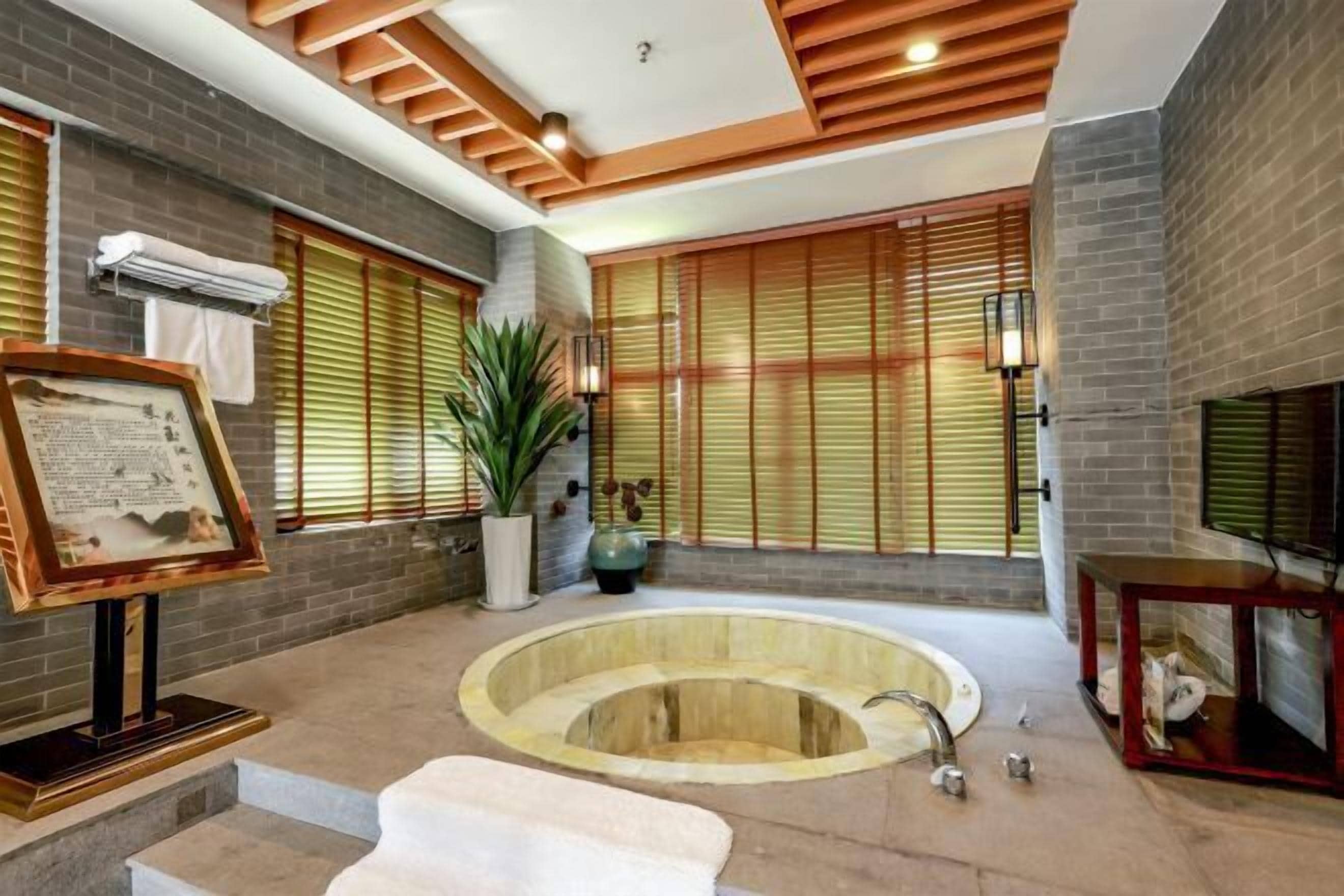 Uma área de spa com hidromassagem, ripas de madeira nas janelas e um painel informativo emoldurado.
