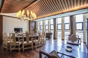 Um quarto espaçoso com uma grande mesa de jantar, assentos confortáveis, televisão e amplas janelas com vista.