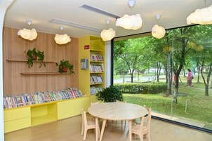 Uma biblioteca com estantes, uma mesa redonda e cadeiras.