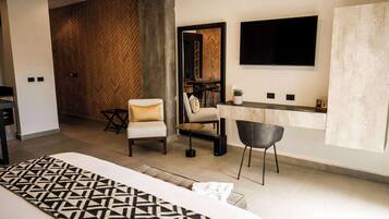 Quarto de hotel moderno com uma cama grande, uma escrivaninha, uma cadeira e televisão na parede.