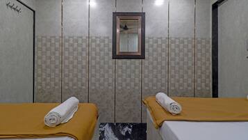 Quarto de hotel com duas camas, um espelho e parede estampada.