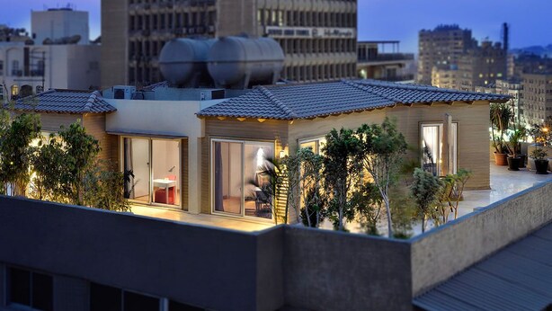 Terraço no telhado com duas divisões, área de estar ao ar livre e plantas em vasos.