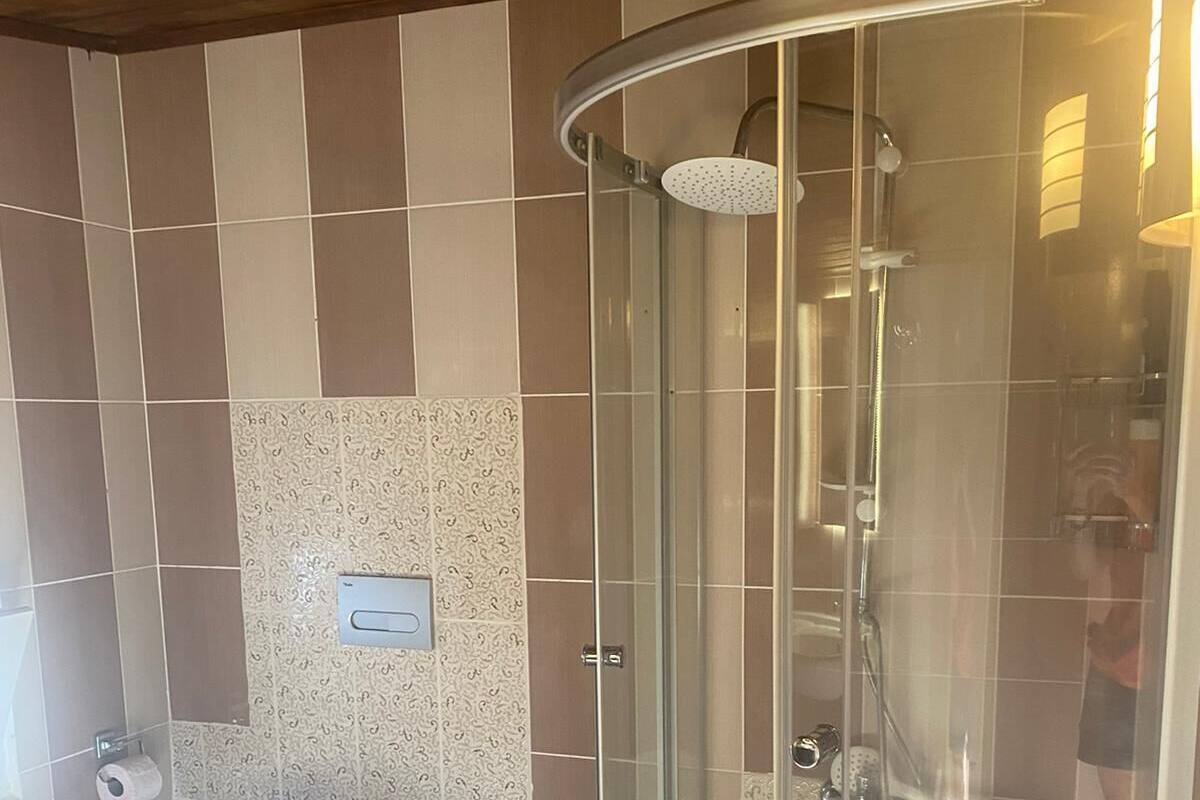 Uma casa de banho moderna com chuveiro separado por vidro, sanita e lavatório.