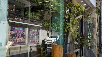 Um edifício moderno com fachada de vidro, detalhes em pedra e área externa com mesas.