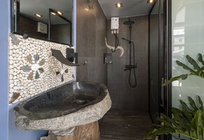 Casa de banho moderna com lavatório de pedra, chuveiro com esguicho manual e ar condicionado de parede.