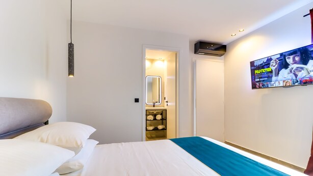 Quarto de hotel com cama, televisão na parede, guarda-roupa e espelho.
