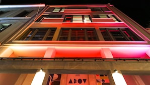 Um edifício com sinalização iluminada que diz "ABOV ATHENS" e um design arquitetônico moderno.