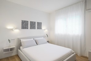 Um quarto moderno com uma cama, mesas de cabeceira e obras de arte na parede.