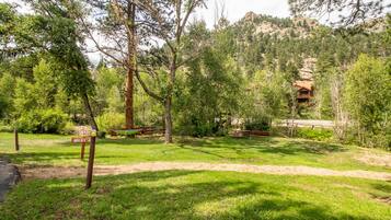 Um camping com mesas de piquenique, uma cabana de madeira e um letreiro.