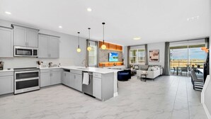 Uma cozinha moderna com ilha central, eletrodomésticos embutidos e iluminação pendente.