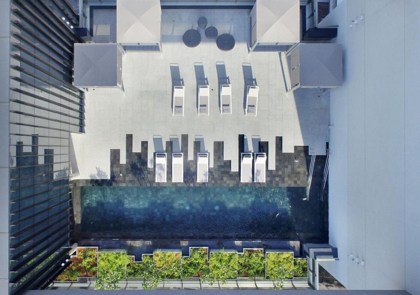Vista aérea de uma área de piscina no terraço, com espreguiçadeiras e um pequeno jardim.