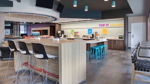 Uma área de café da manhã moderna com balcão, banquetas e assentos.
