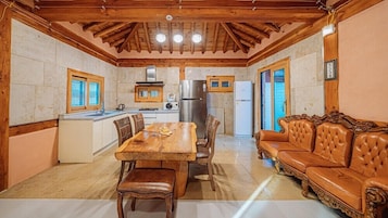 Uma cozinha espaçosa com armários de madeira, uma mesa de jantar com cadeiras, um sofá e uma geladeira.