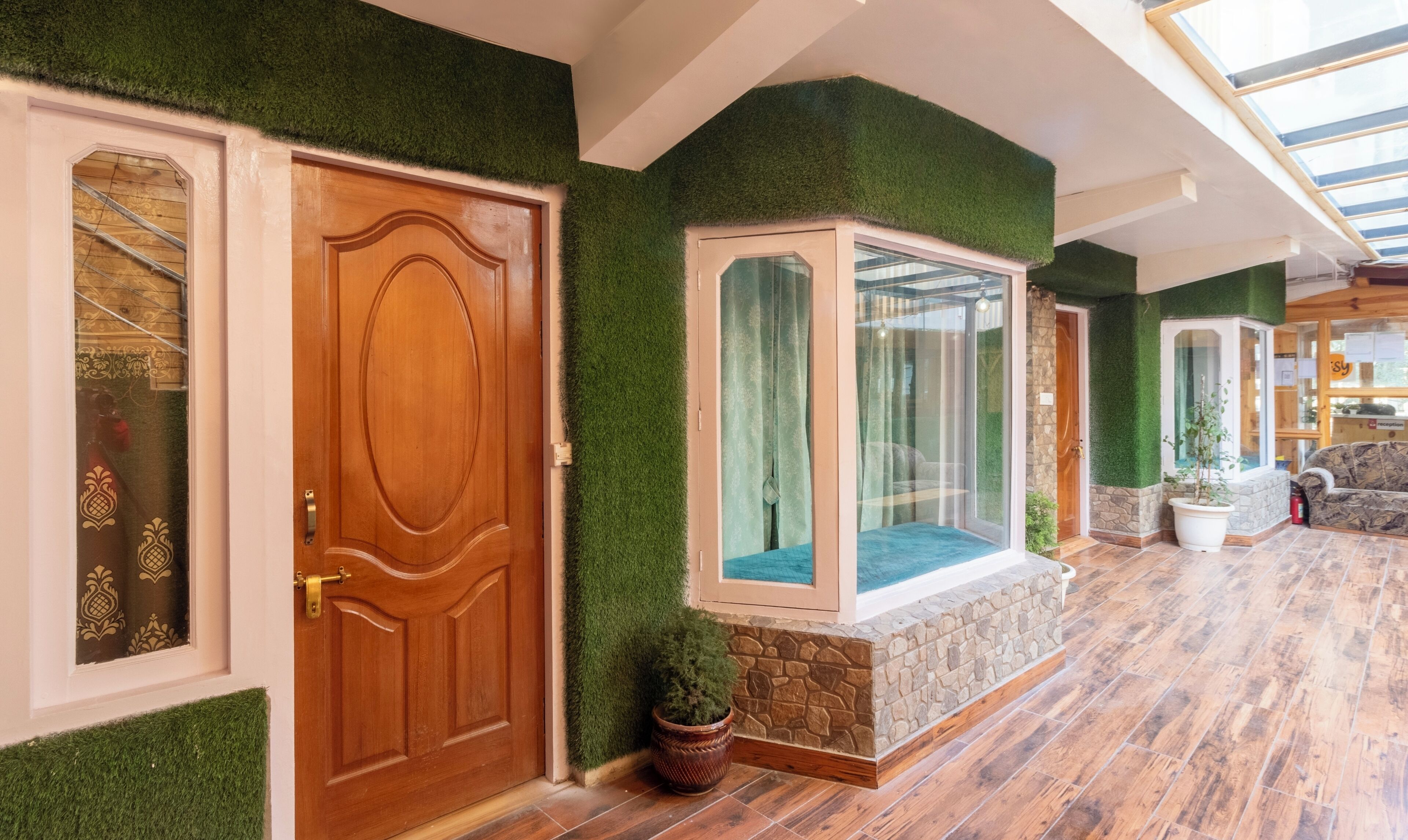 Um interior moderno com porta de madeira, detalhes em parede verde e uma parede de pedra decorativa.