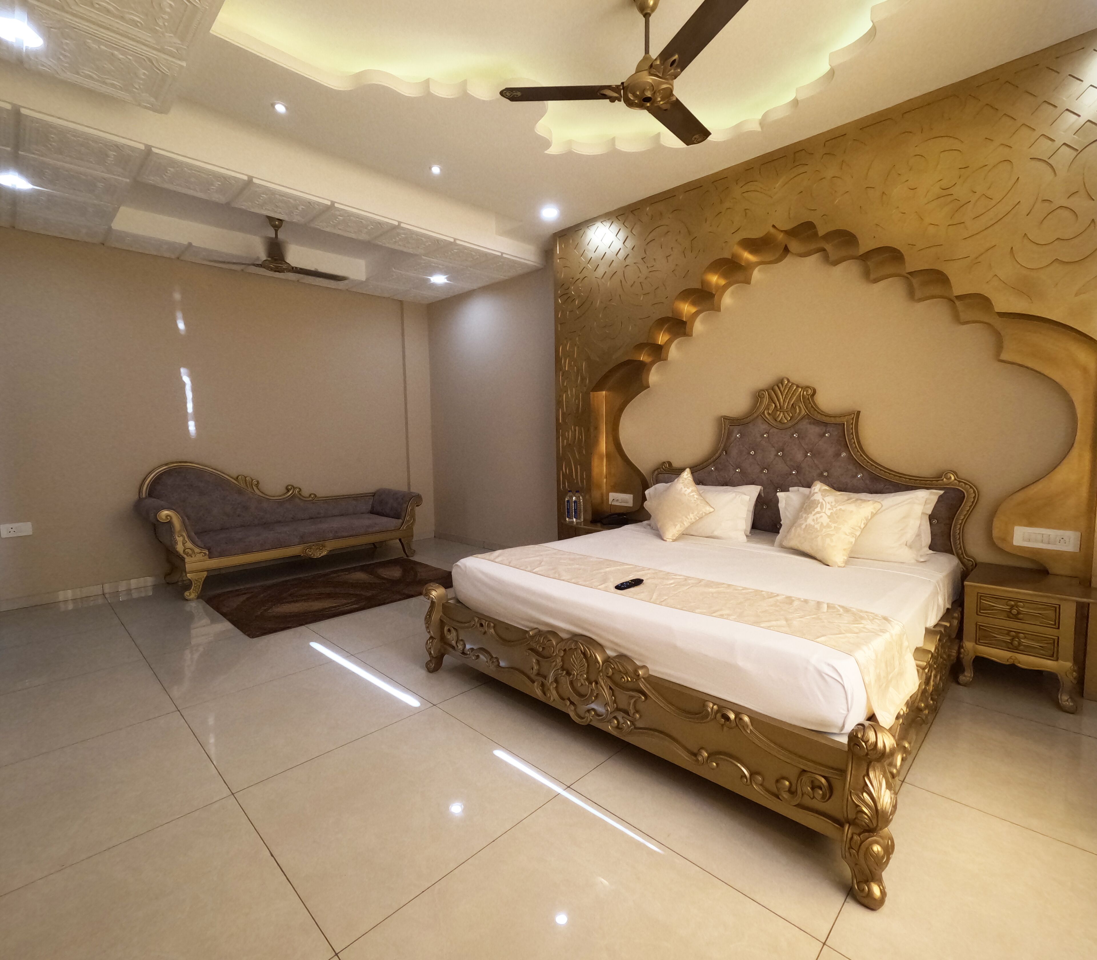 Um quarto luxuoso com uma cama grande e ricamente decorada, um sofá e um ventilador de teto.