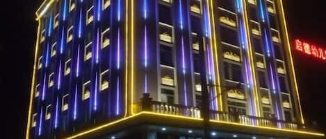 Um edifício com vários andares, entrada destacada e sinalização iluminada.