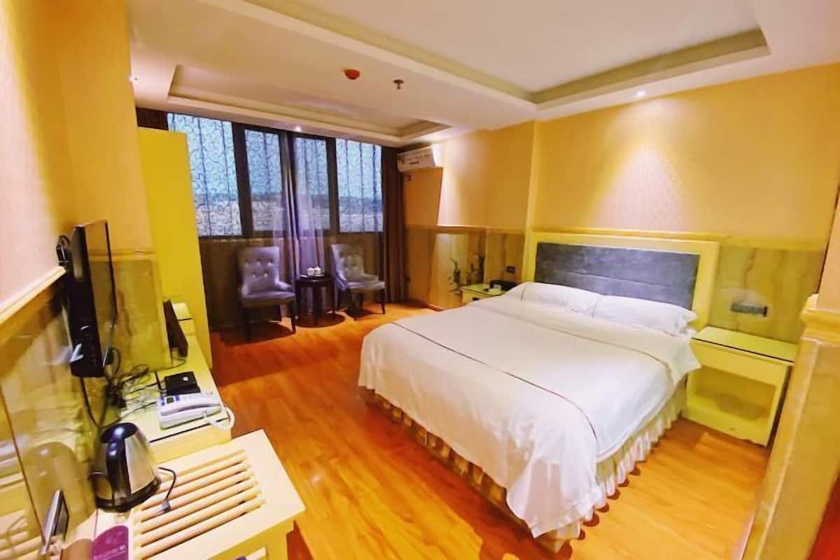 Quarto de hotel com cama, escrivaninha, computador, cadeira e televisão.