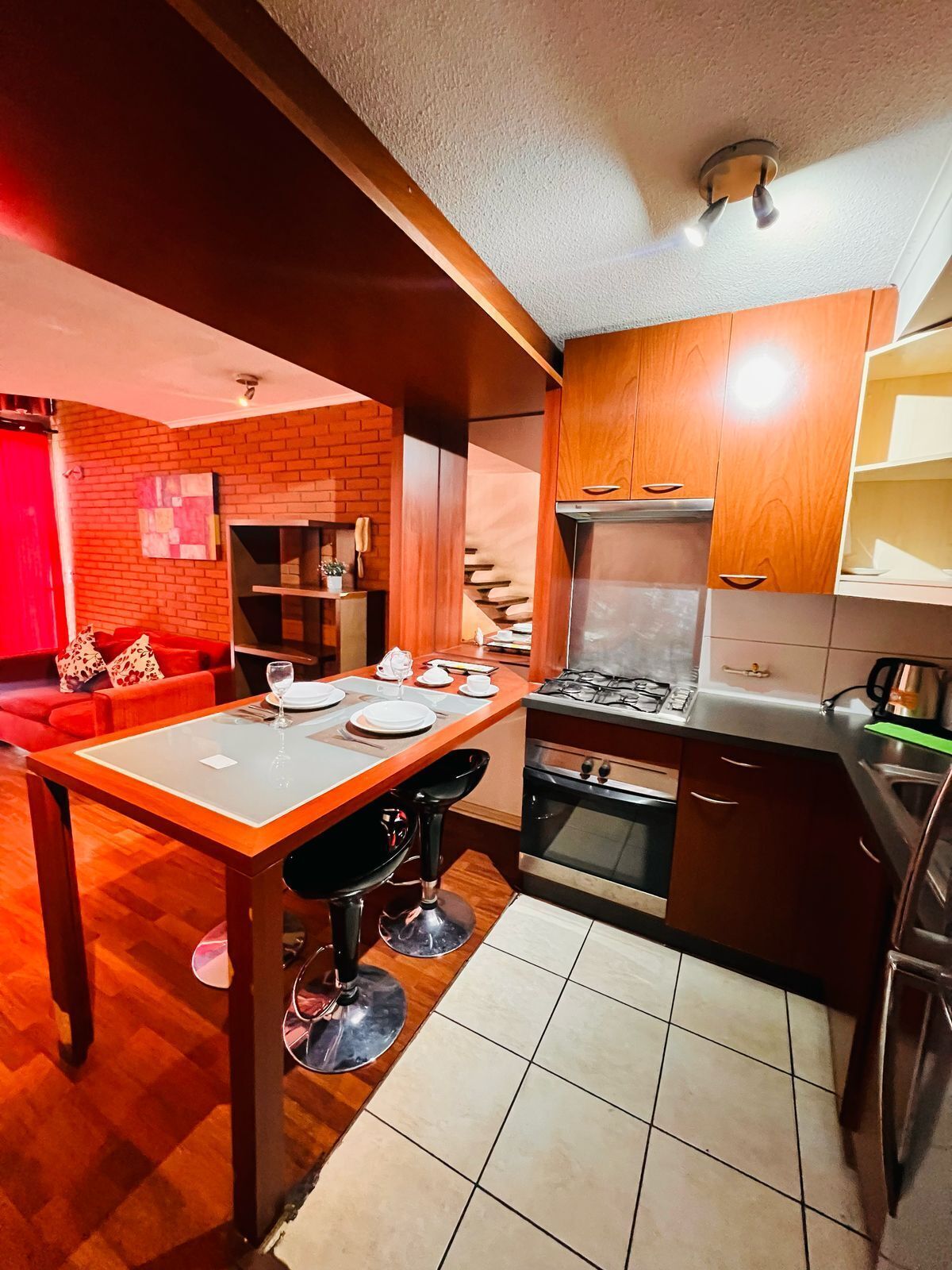 Cozinha moderna com armários de madeira, fogão a gás e área de refeições com mesa e cadeiras.