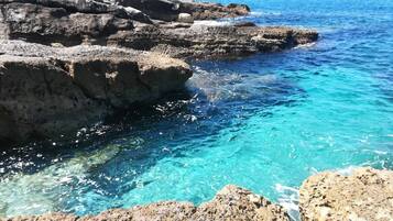 Paisagem costeira com formações rochosas e água azul cristalina.