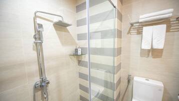 Uma casa de banho moderna com chuveiro em cabine de vidro, sanita e porta-toalhas.
