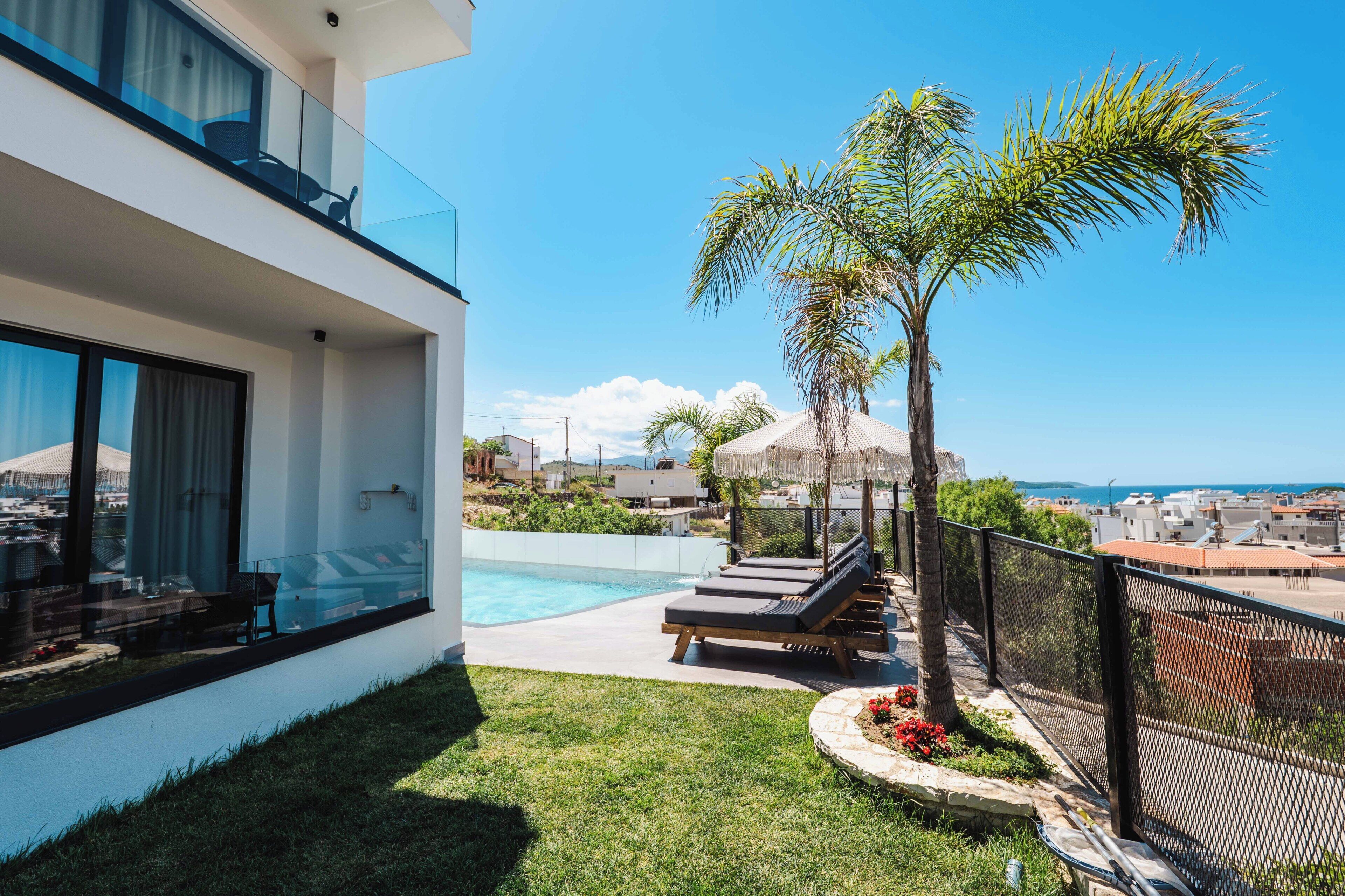 Uma casa moderna com piscina, espreguiçadeiras e vista para o mar.