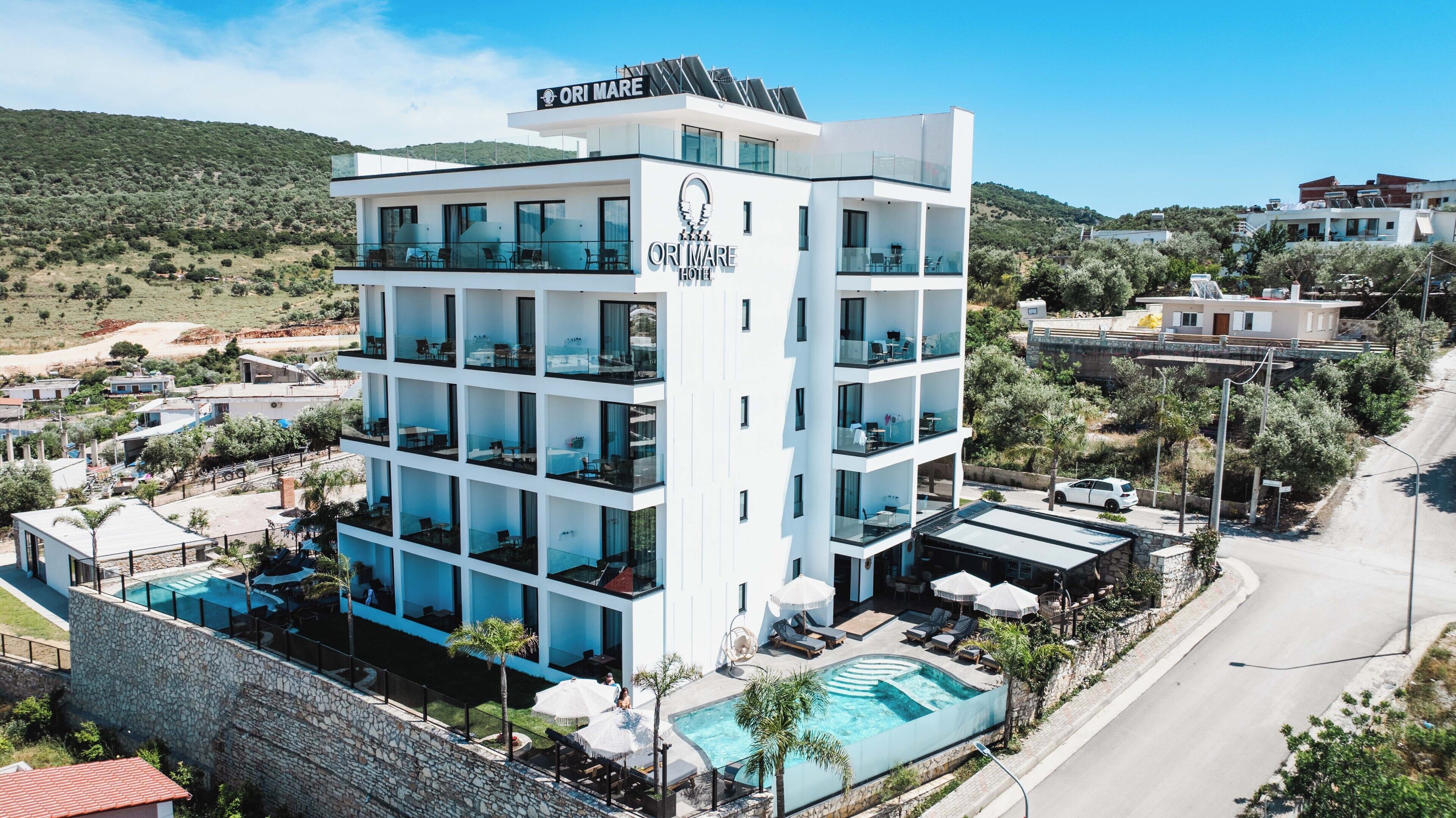 Um hotel moderno com várias varandas, piscina e vista para a paisagem circundante.