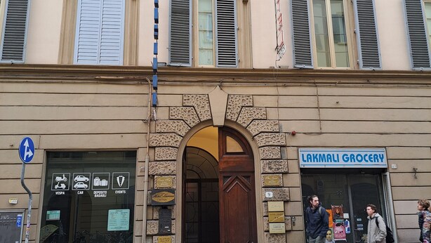 Um edifício com entrada no andar térreo, uma placa indicando 'Lakmali Grocery' e uma porta com arco de pedra.