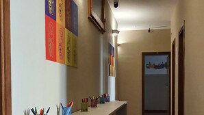 Um corredor com uma mesa de recepção, obras de arte coloridas na parede e piso revestido de azulejos.