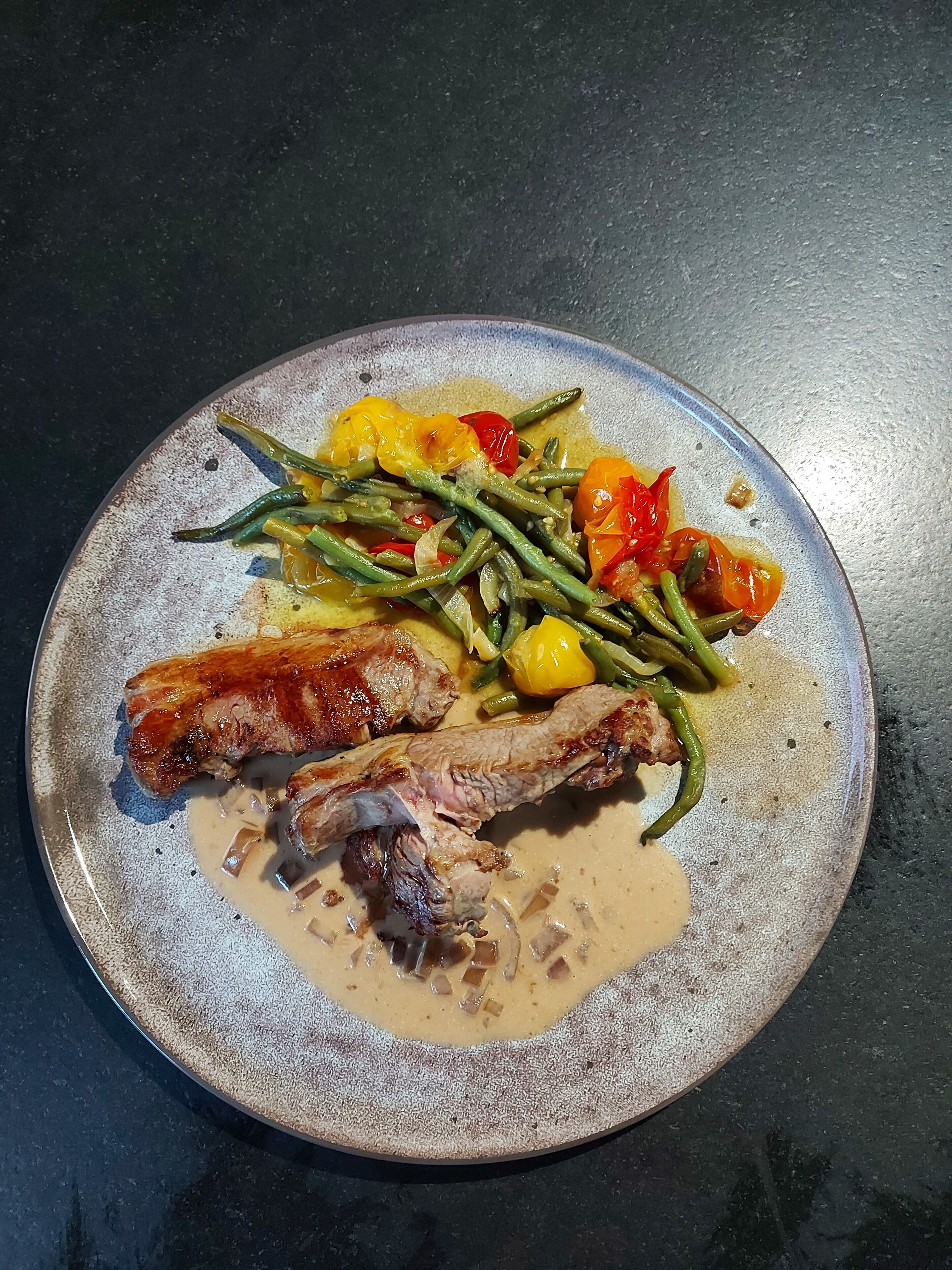 Um prato com carne grelhada, vagem e pimentões.